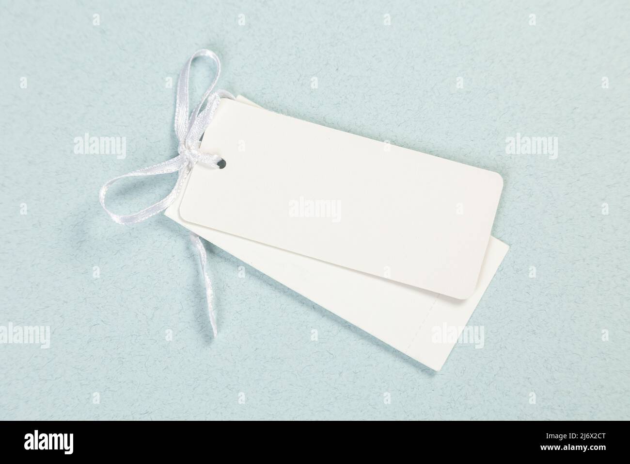 An empty white price tag lies on a gray-blue background with a soft ...