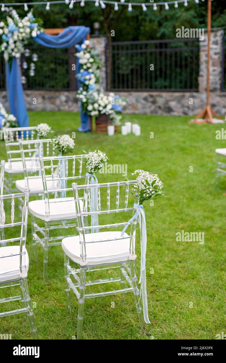 Flower-decorated chairs for guests at an outdoor wedding ceremony. Soft ...