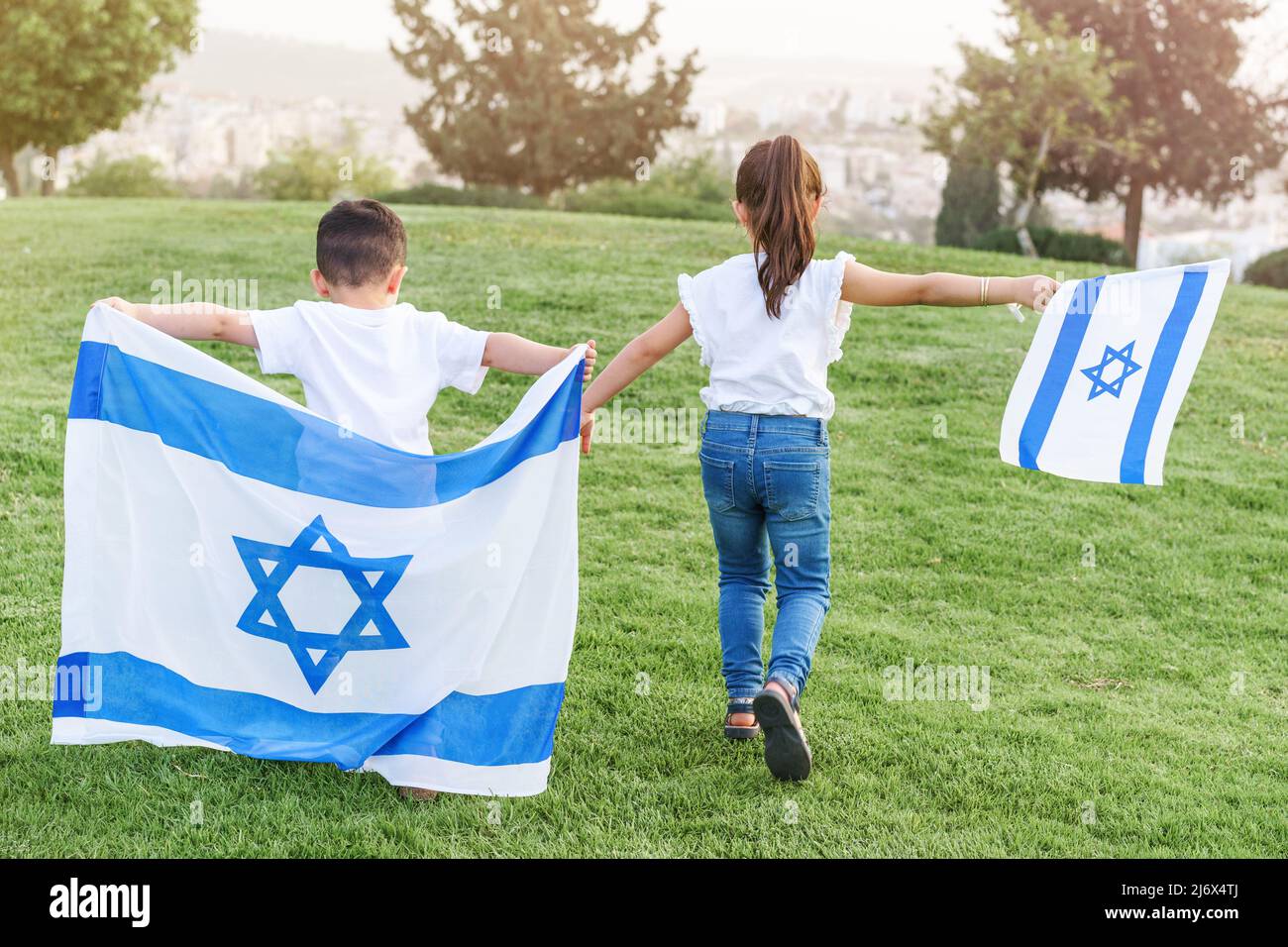 Young children running with Israeli flag. Rear view faceless little ...