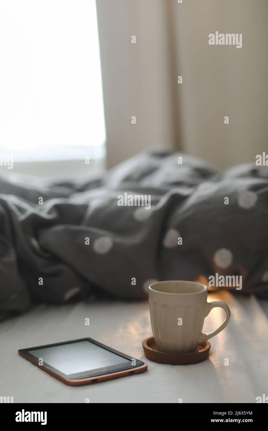 Tablet and a cup of coffee in bed on the sheets. Good morning ...