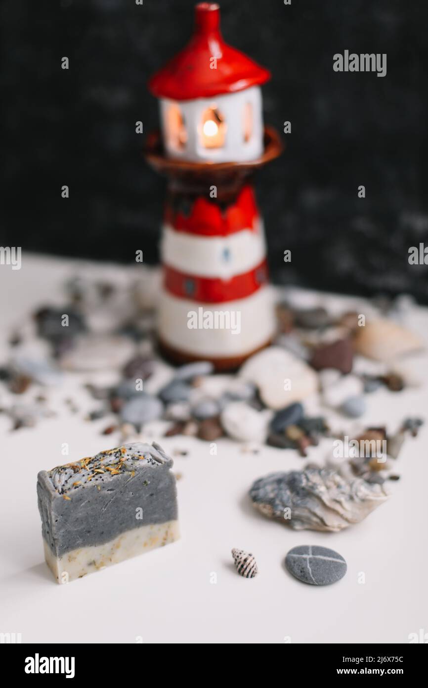 A small decorative lighthouse with sea shells and pebbles. Summer ...