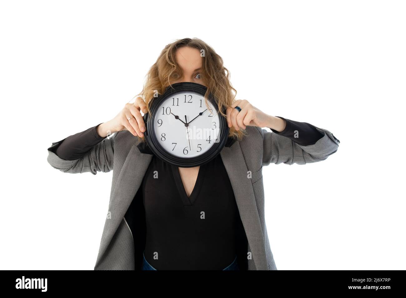 A shocked woman holds a large clock in her hands on a white background ...