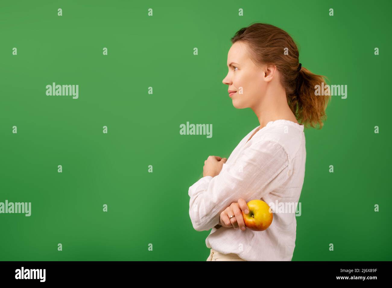 Adult good looking woman in white shirt holds fresh apple on green ...