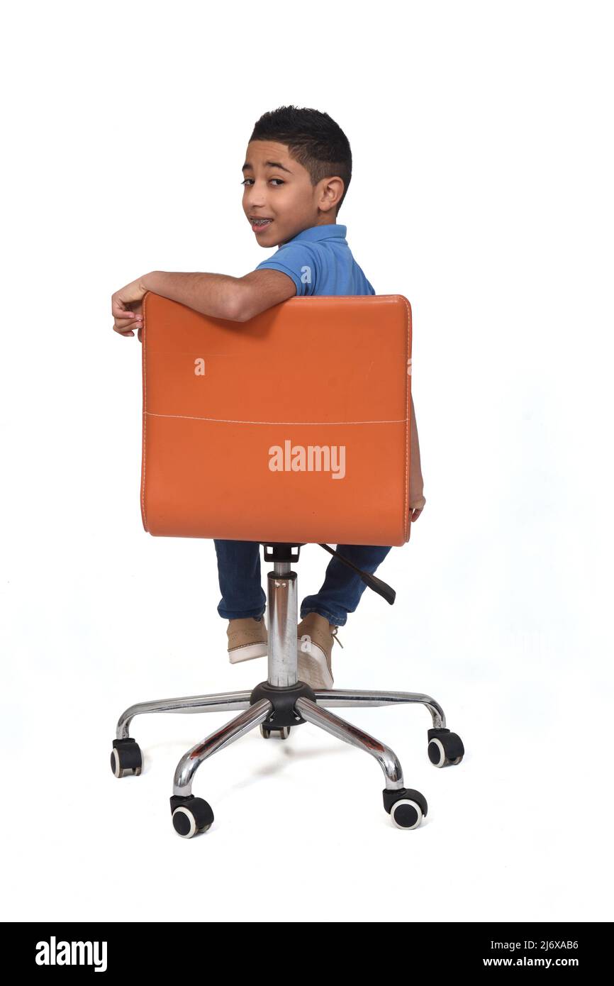 rear view of a boy who is sitting on a chair and turns on white ...