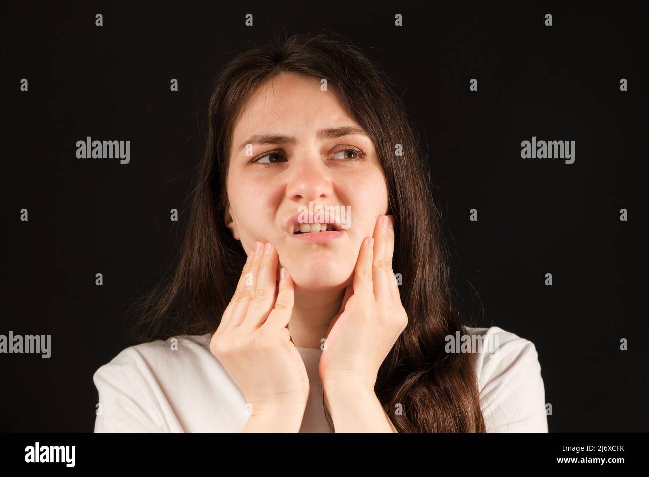 A woman holds her hands to a sore temporomandibular joint, dysfunction ...