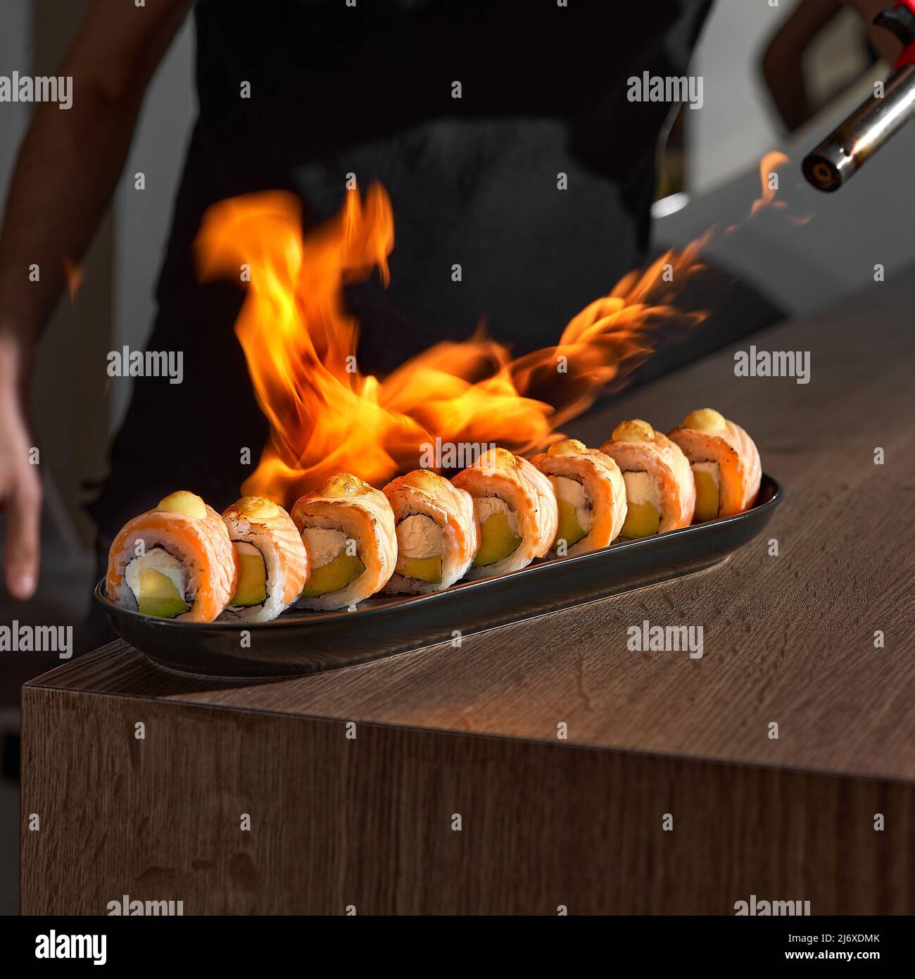 Restaurant Chef cook preparing salmon filet flambe in open kitchen ...