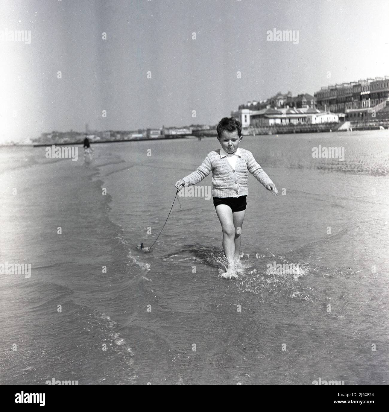 1950s, historical, a young boy on a beach at the sea's edge or ...
