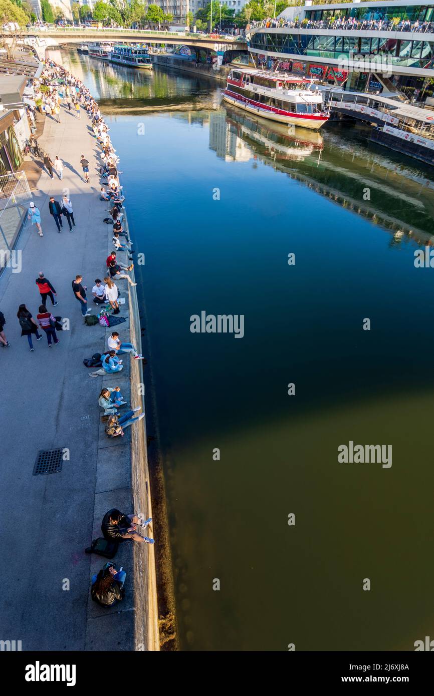 Wien, Vienna: river Donaukanal (Danube Canal), people sit on bank reinforcement, Schwedenplatz ...