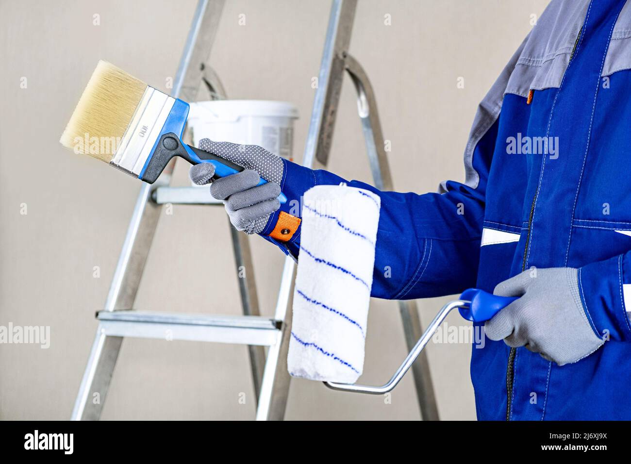 The builder is a painter in a blue suit, a brush in his hand and ...