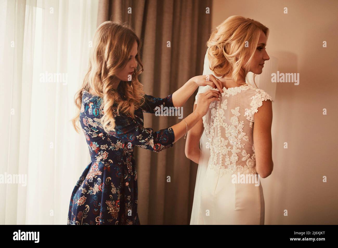 Wedding. Bridesmaid preparing bride for the wedding day. Bridesmaid ...