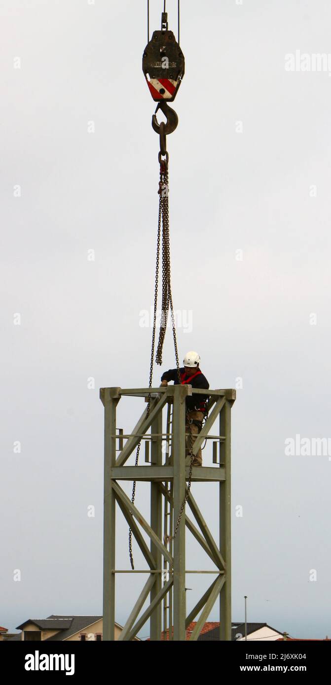 A construction worker undoing the chains from the mast section of a ...