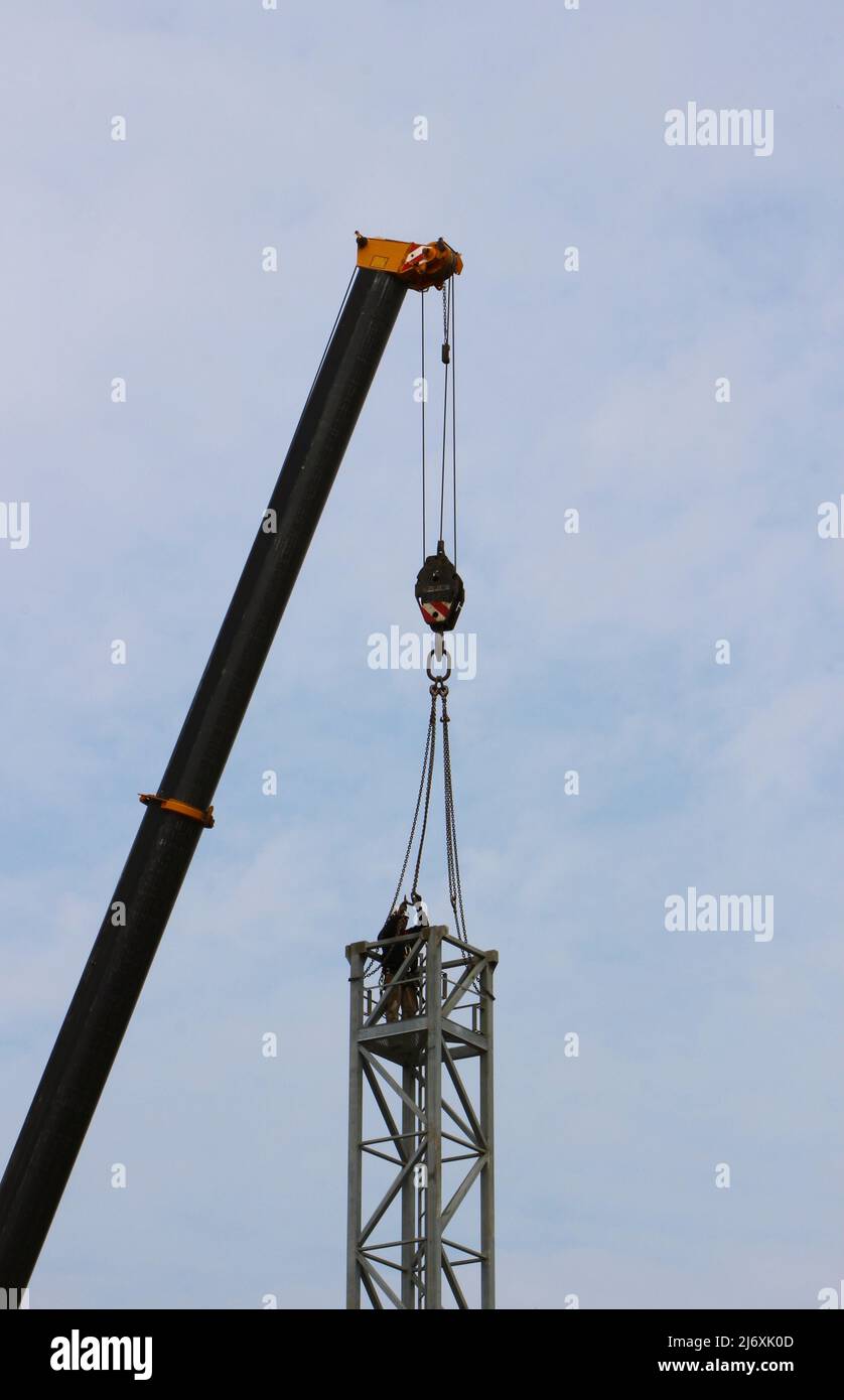 A construction worker undoing the chains from the mast section of a ...