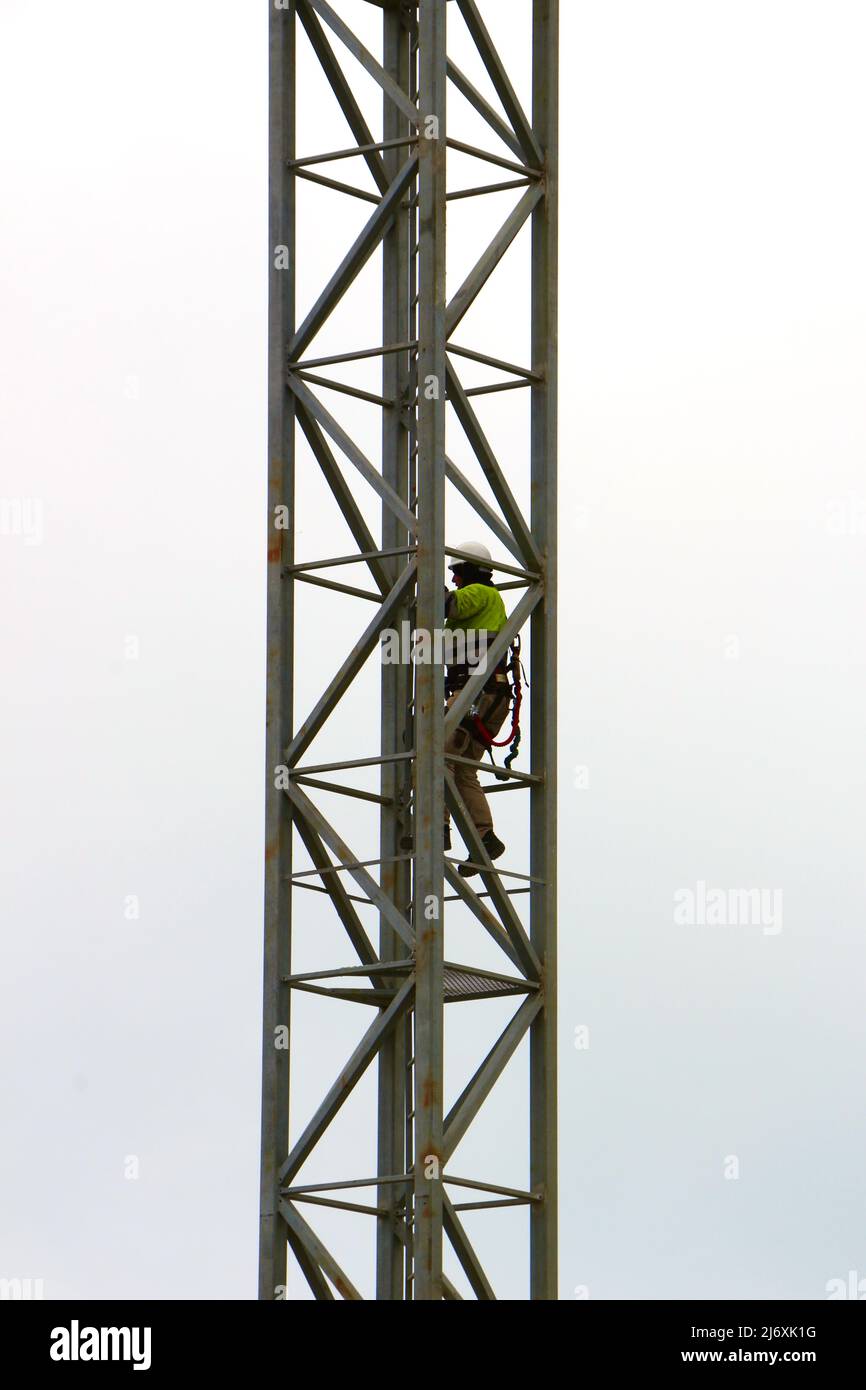 A construction worker climbing the ladder inside the mast of a tower ...