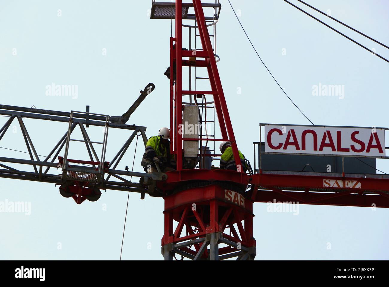 Construction workers fix the horizontal jib in position on a tower ...