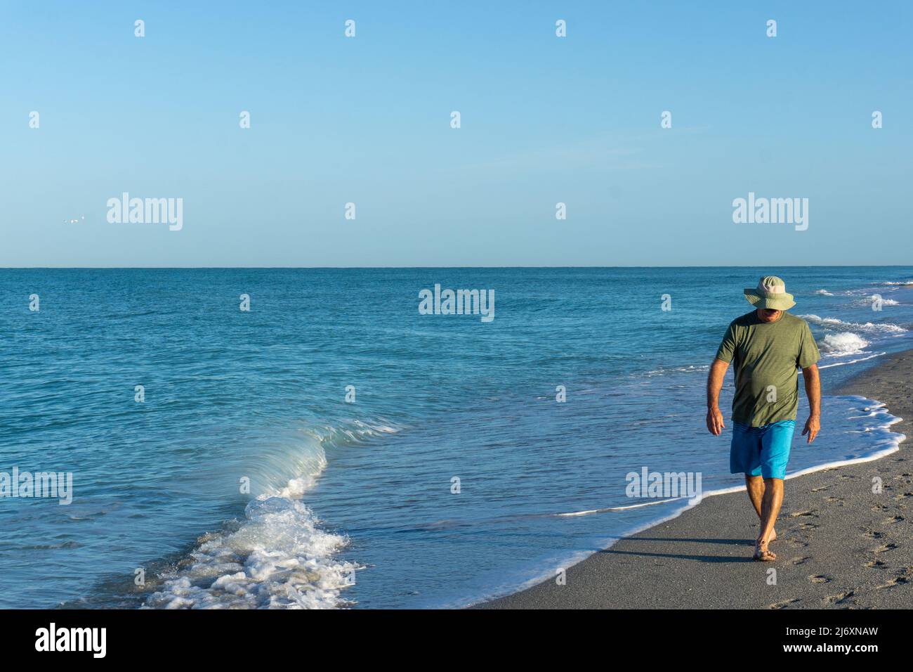 Old retired man walks down beach on Florida gulf coast Stock Photo - Alamy