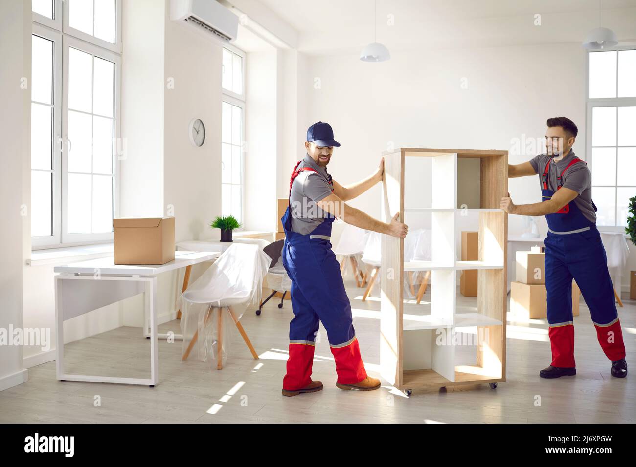Male movers help client with furniture unloading Stock Photo - Alamy