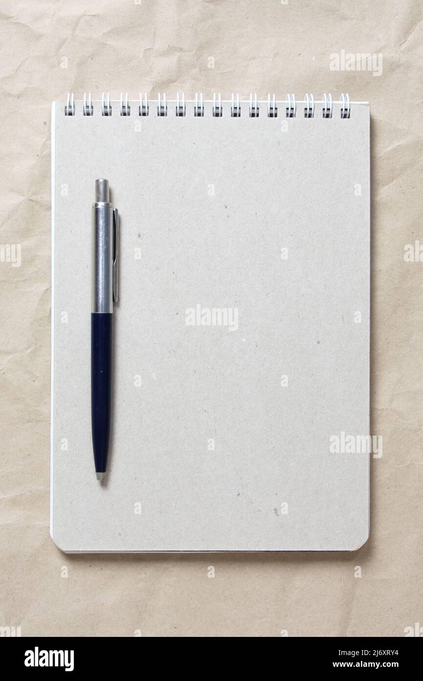 Gray notepad with white coiled spring and pen on a background of beige ...