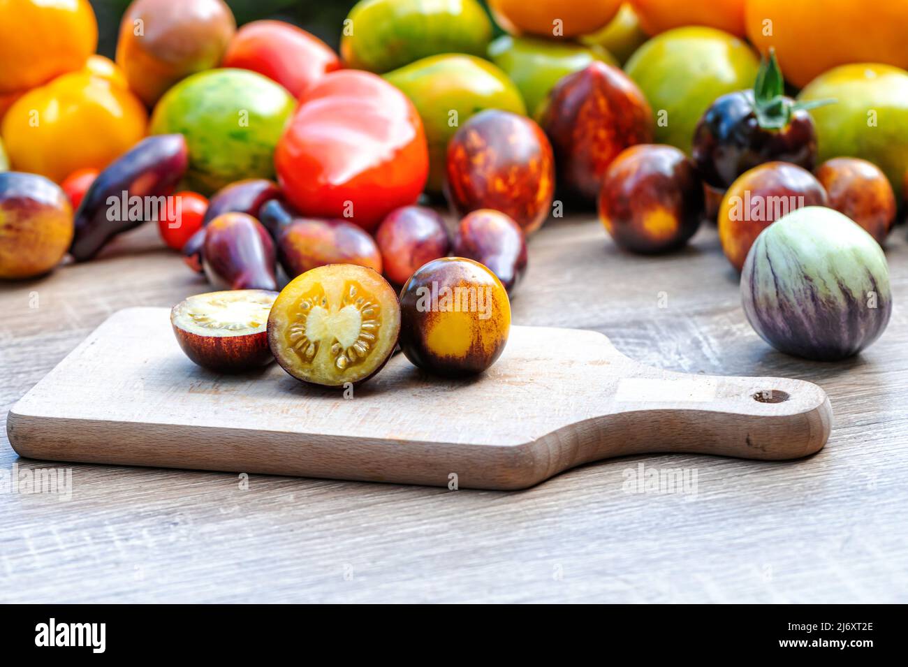 table with a chopping board with sliced tomatoes and different colored ...