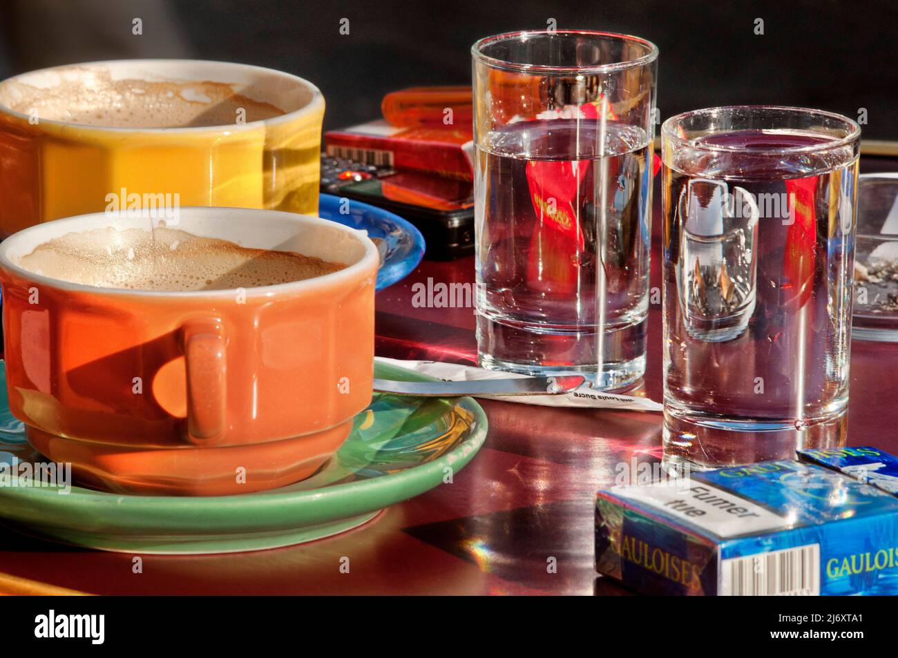 Two cups of coffee, two glasses of water, a pack of cigarettes on a ...