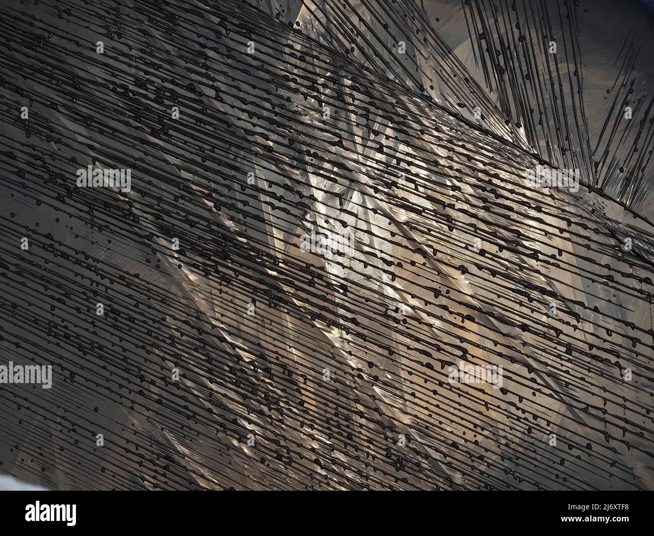 Graphic image of linear creases in highly reflective overlapping black ...