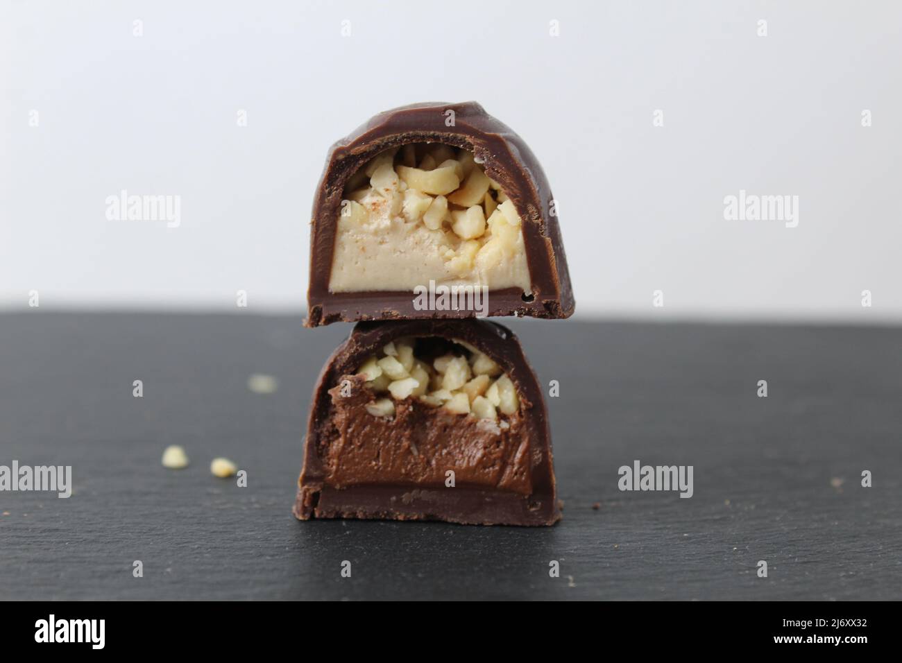 two chocolate candies in a cut with a filling of praline mousse with ...