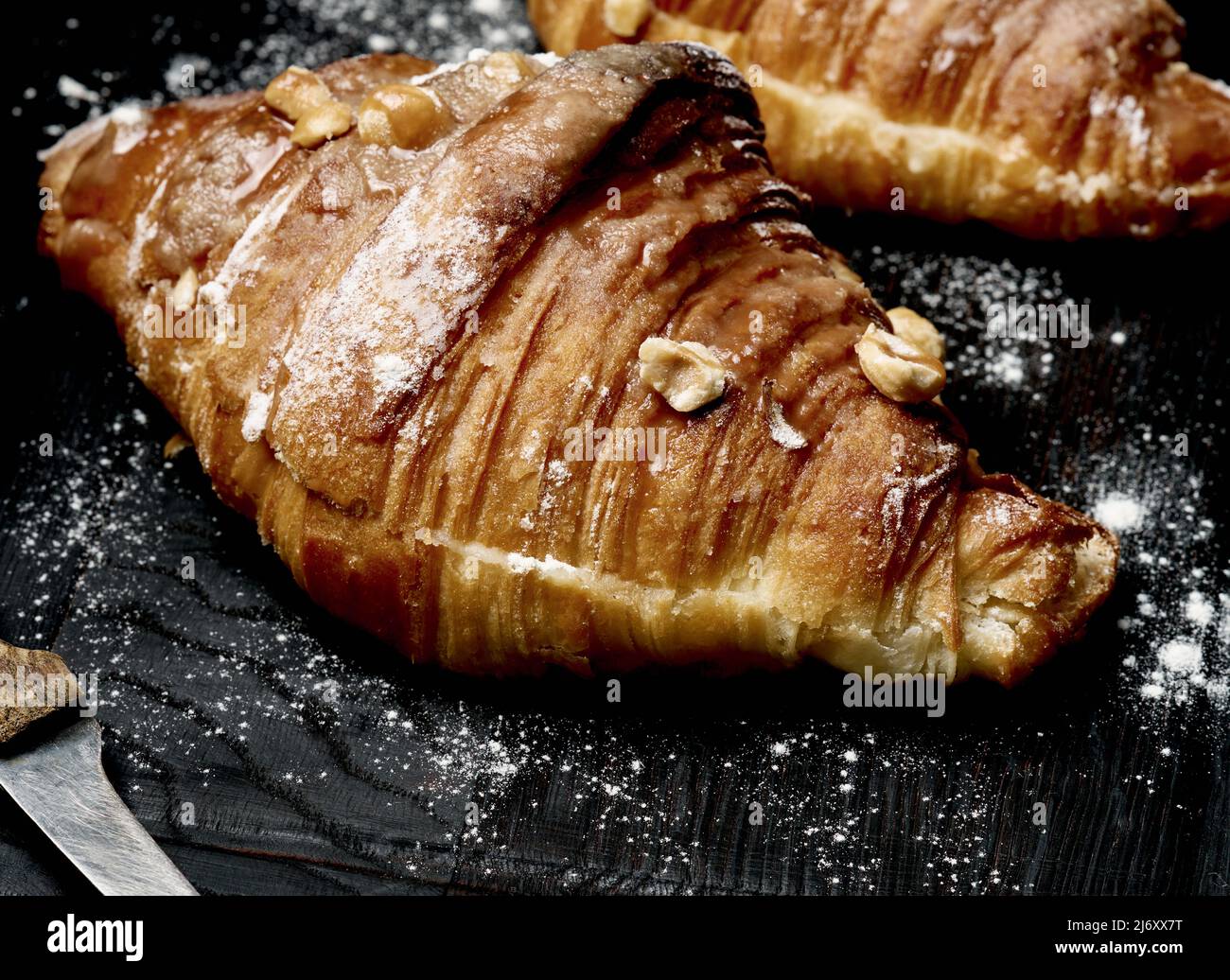 baked croissant on a wooden board and sprinkled with powdered sugar ...