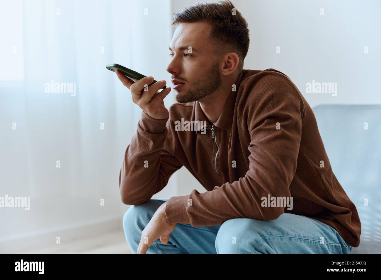 Happy focused friendly young man guy speak at phone record voice ...