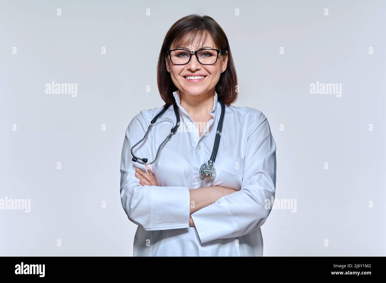 Portrait of smiling female doctor wearing glasses in white uniform with ...