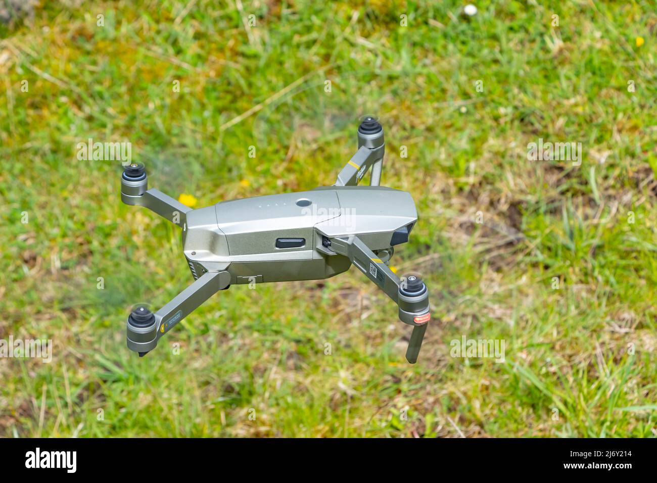 DJI Mavic Pro drone hovering against green grass bushes background ...