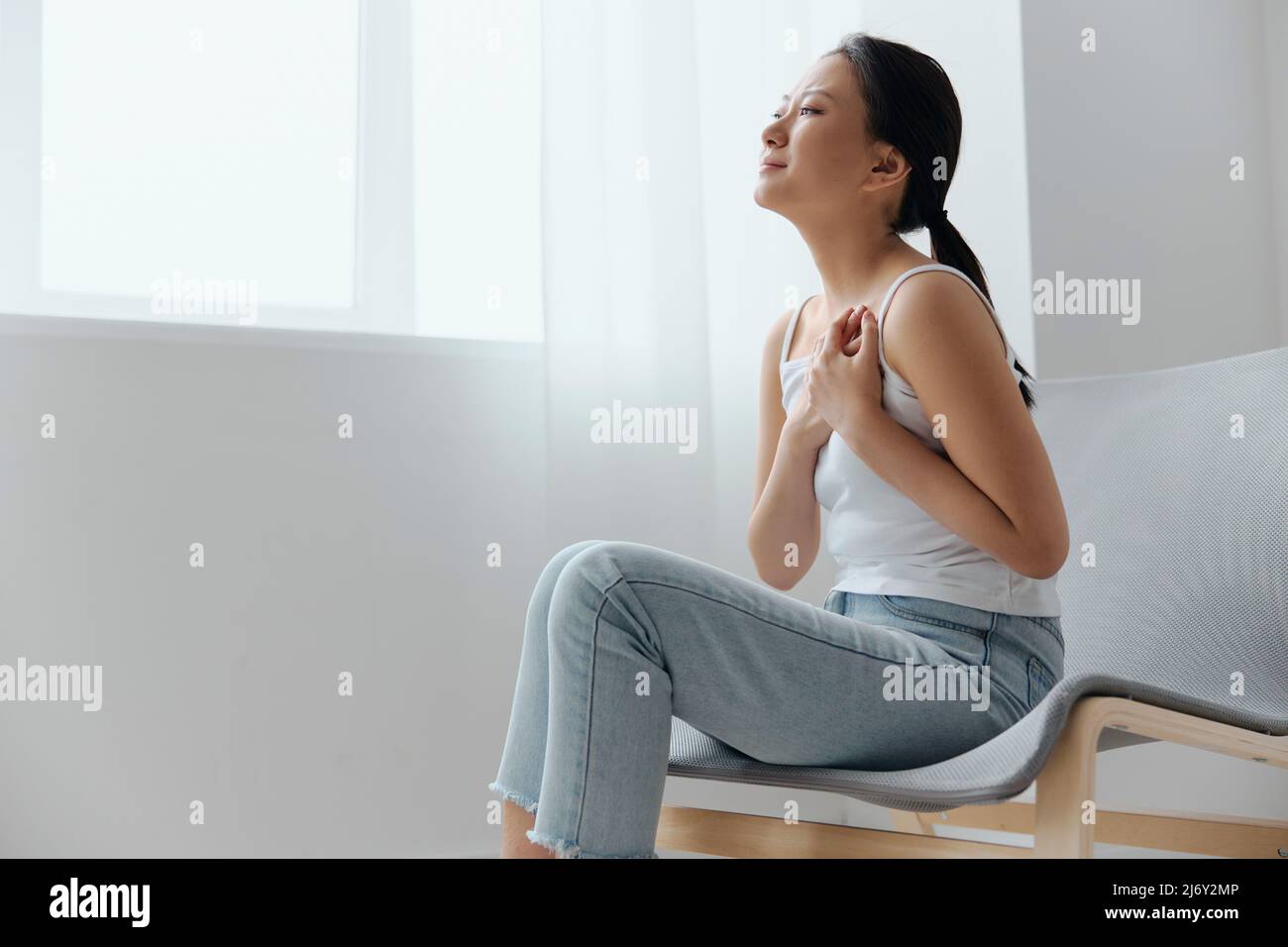 Heart attack. Suffering from pain tanned beautiful young Asian woman ...