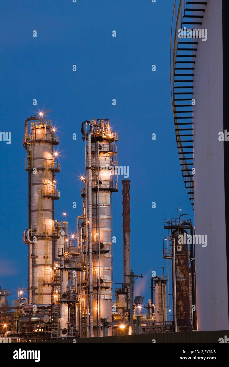 Towers and storage tanks at oil and gas refinery at dusk, Montreal East ...