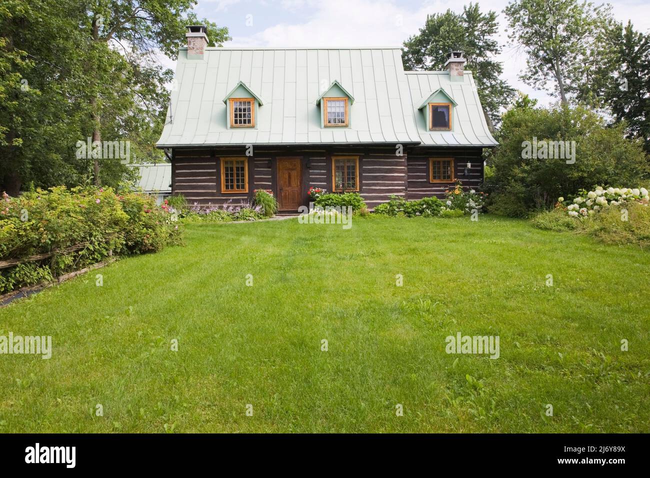 Old 1800s Canadiana style log home with landscaped front yard in summer ...
