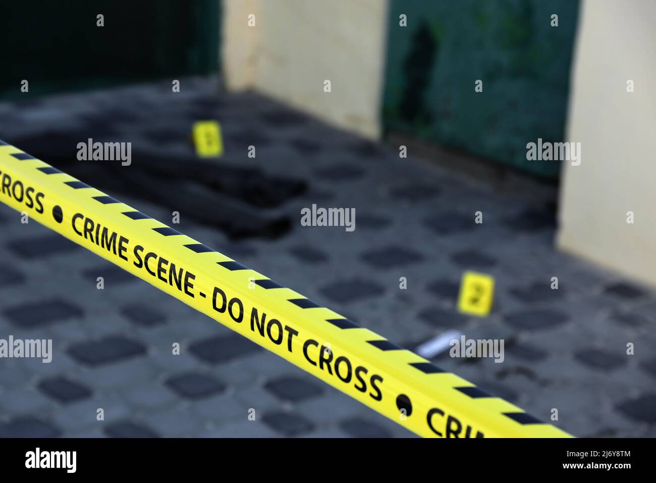 Crime scene tape for covering the area cordon. Yellow tape with blurred forensic law enforcement ...