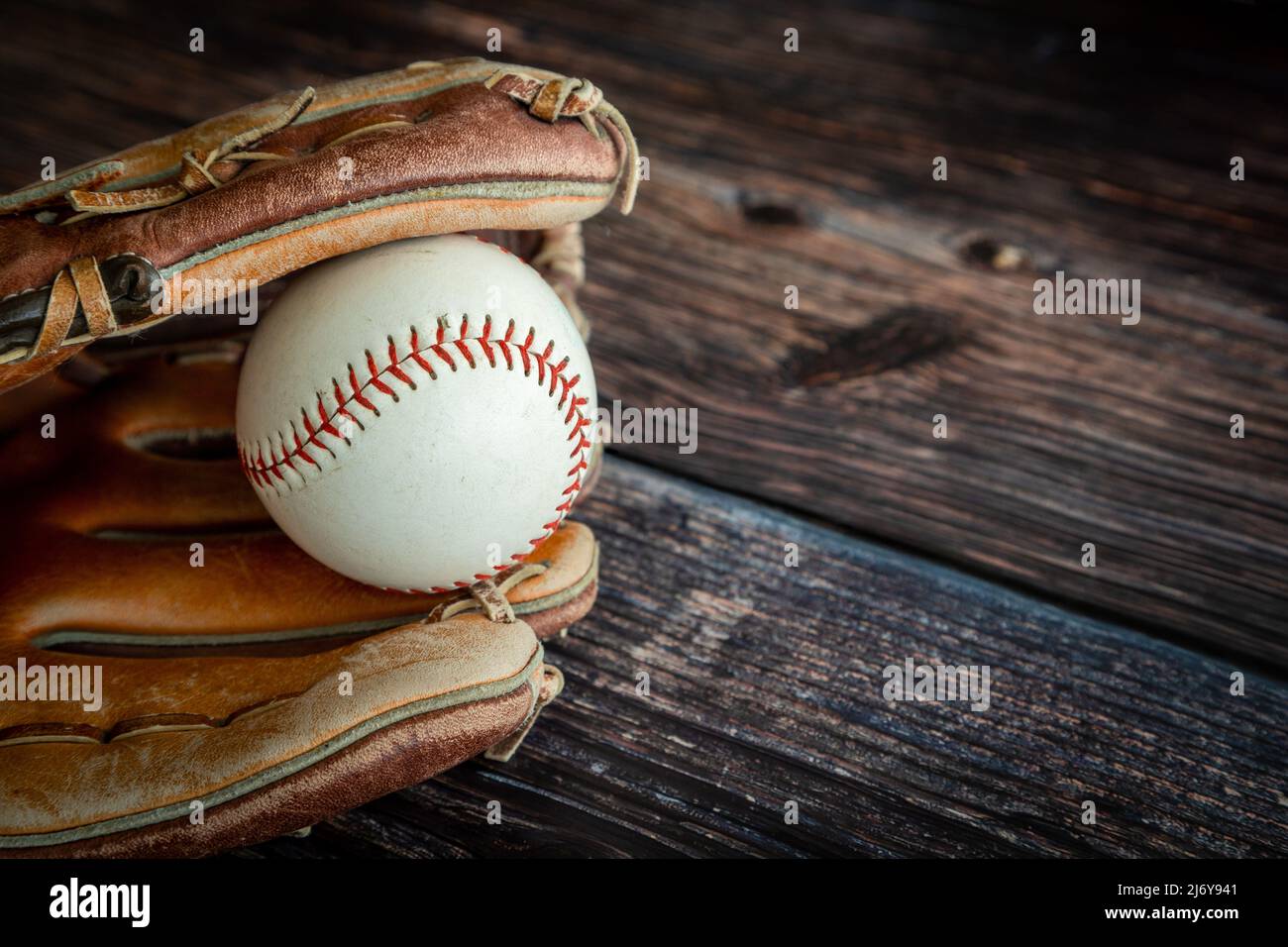 Leather baseball or softball glove with ball on rustic wooden ...