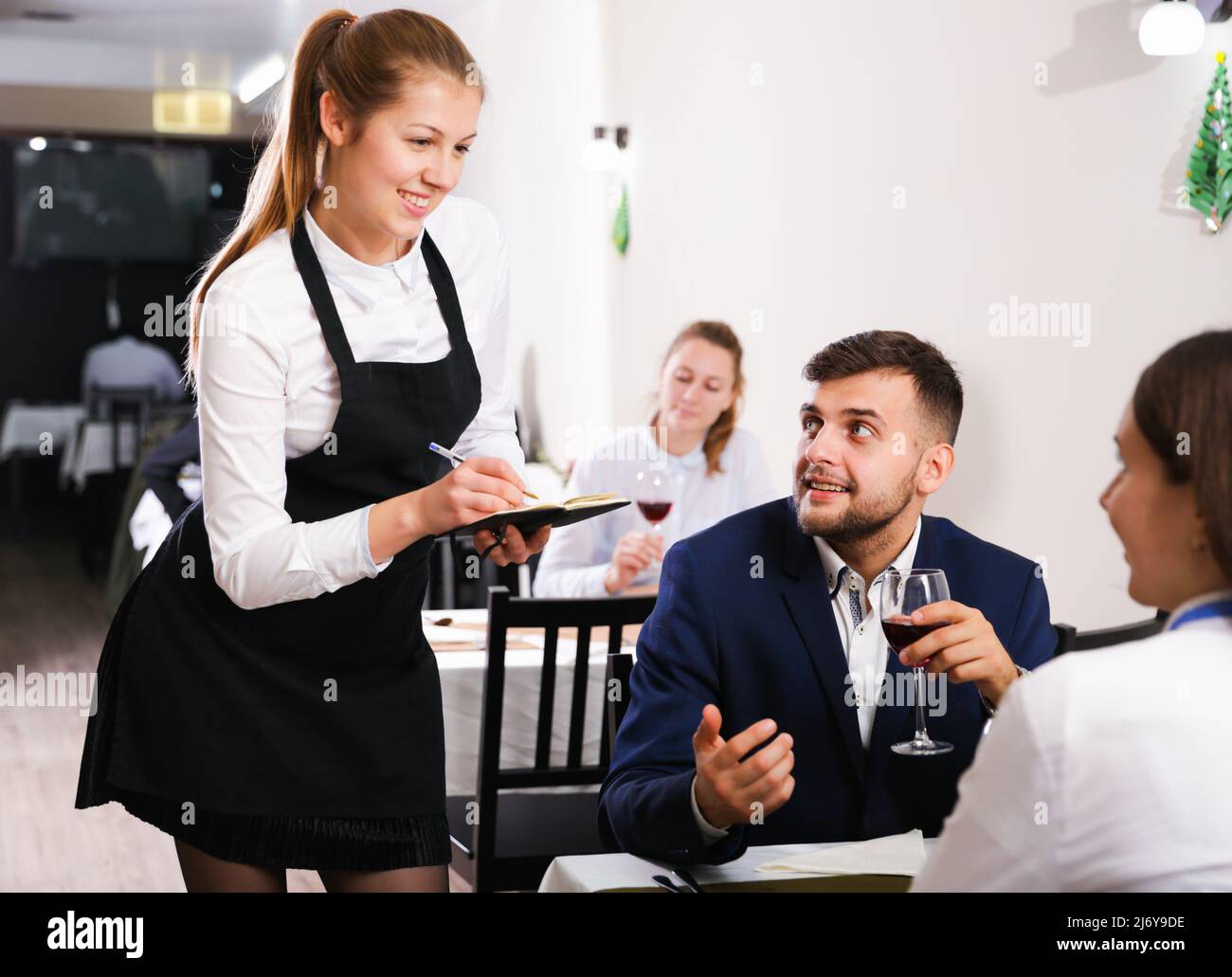 Woman waiter is taking order from clients in restaurante Stock Photo ...
