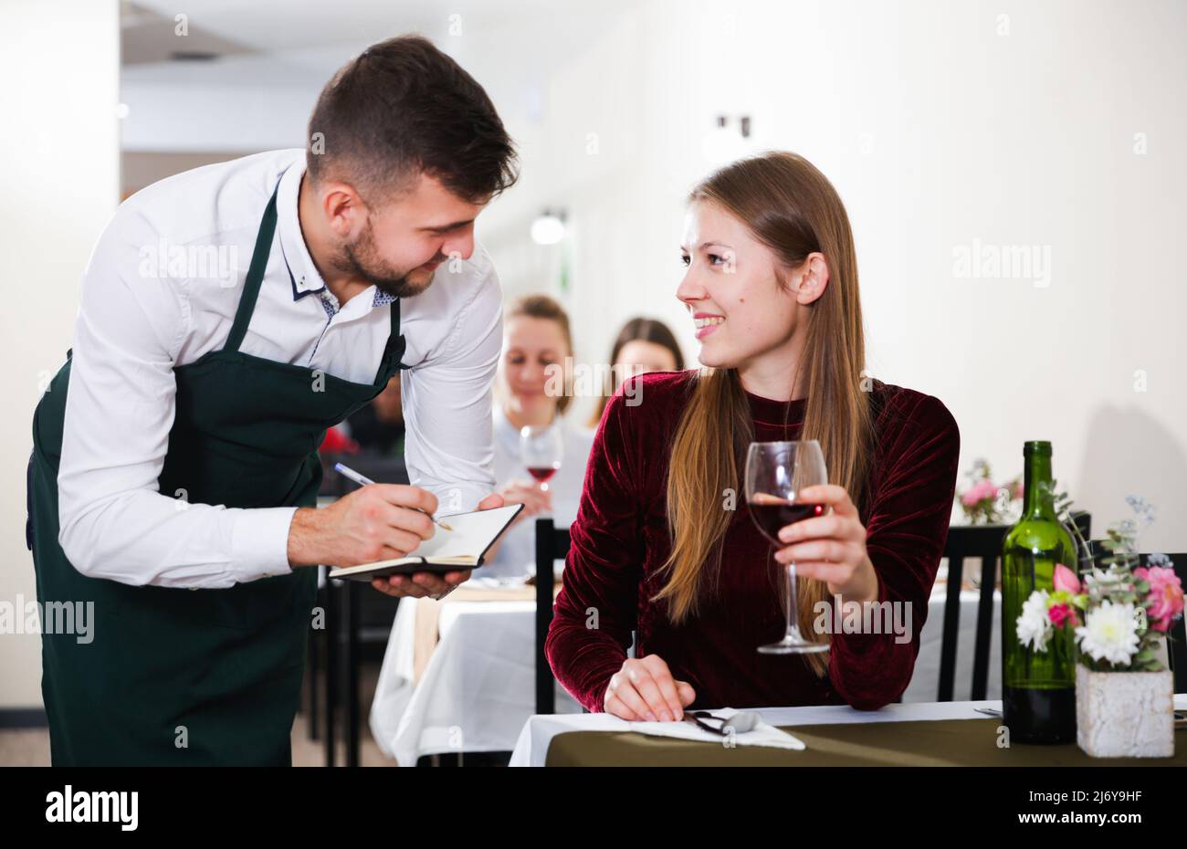 Welcoming waiter is taking order from cheerful woman Stock Photo - Alamy