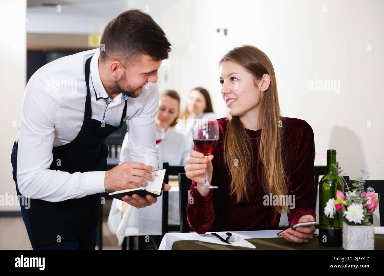 Welcoming waiter is taking order from cheerful woman Stock Photo - Alamy