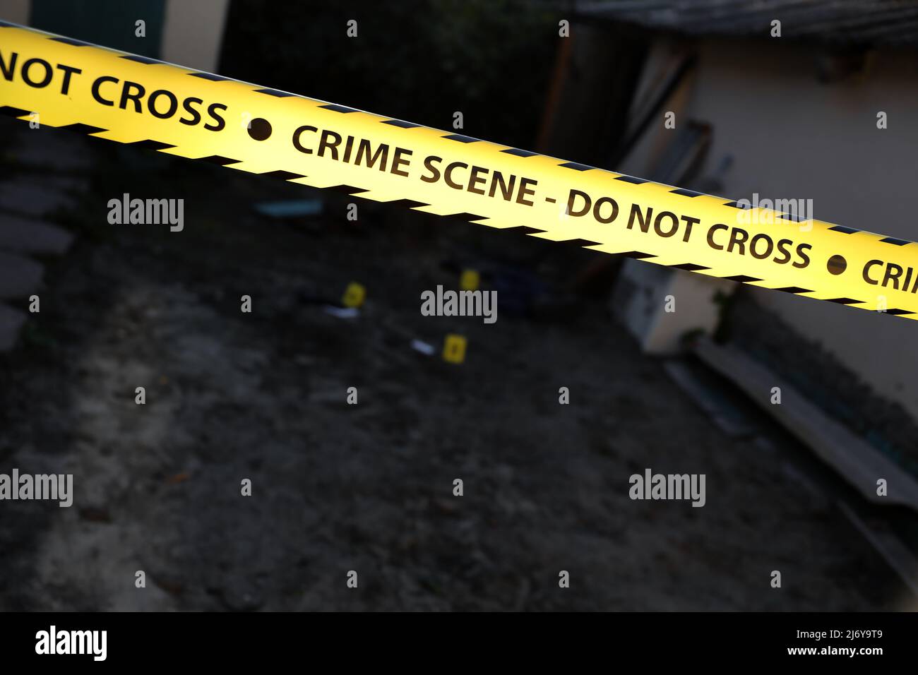 Crime scene tape for covering the area cordon. Yellow tape with blurred forensic law enforcement ...