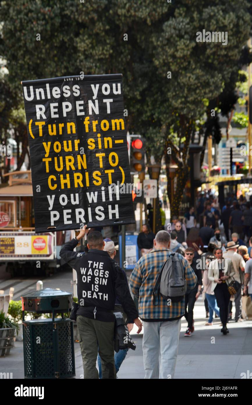 Evangelical Christians with signs and a megaphone walk along a sidewalk ...