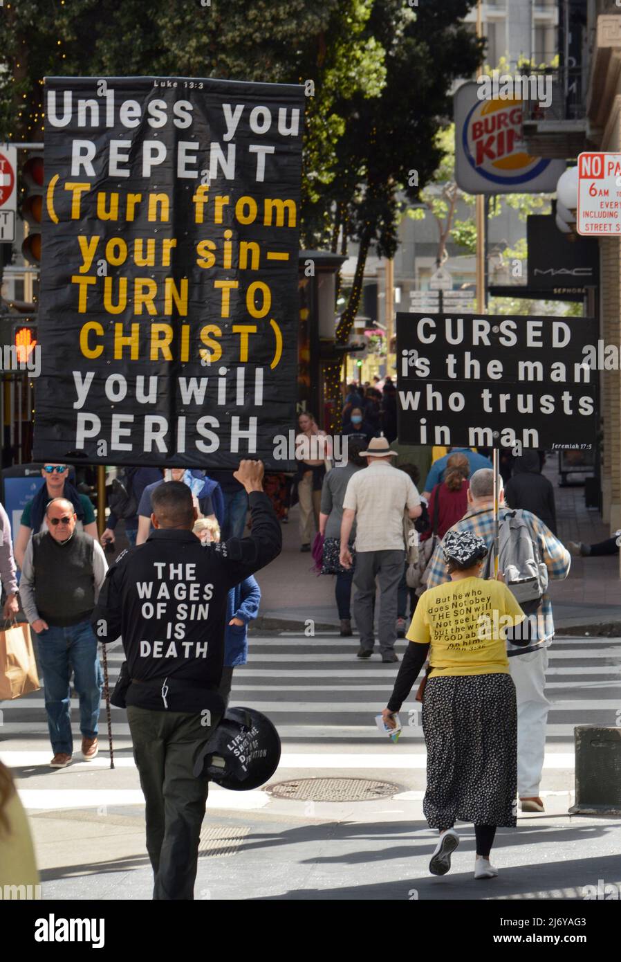 Evangelical Christians with signs and a megaphone walk along a sidewalk ...
