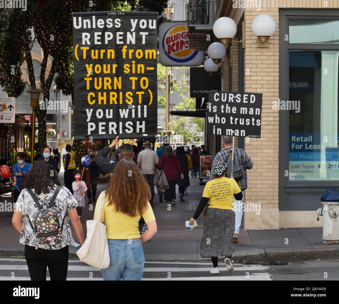 Evangelical Christians with signs and a megaphone walk along a sidewalk ...