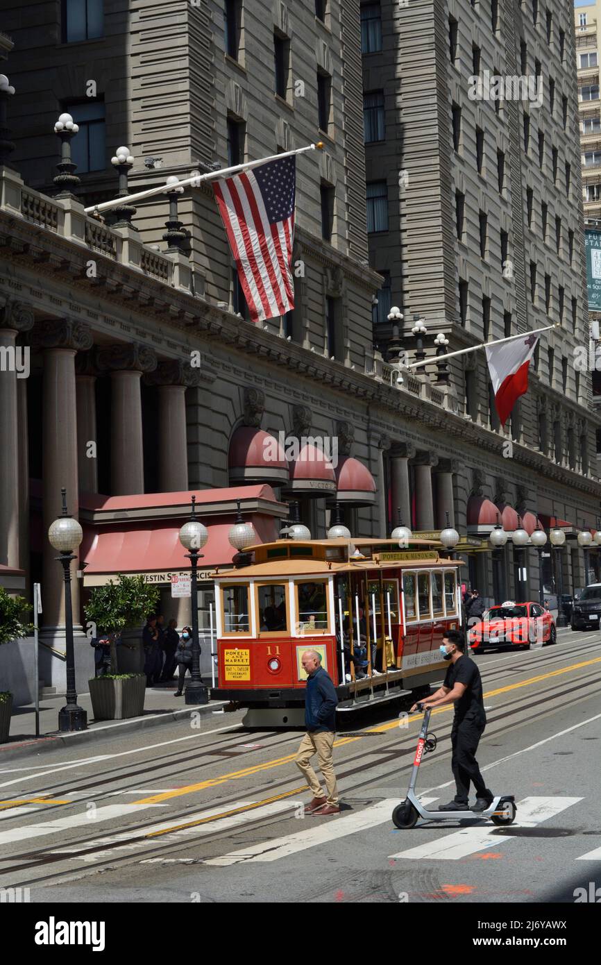 A cable car with passengers passes through Union Square in San ...