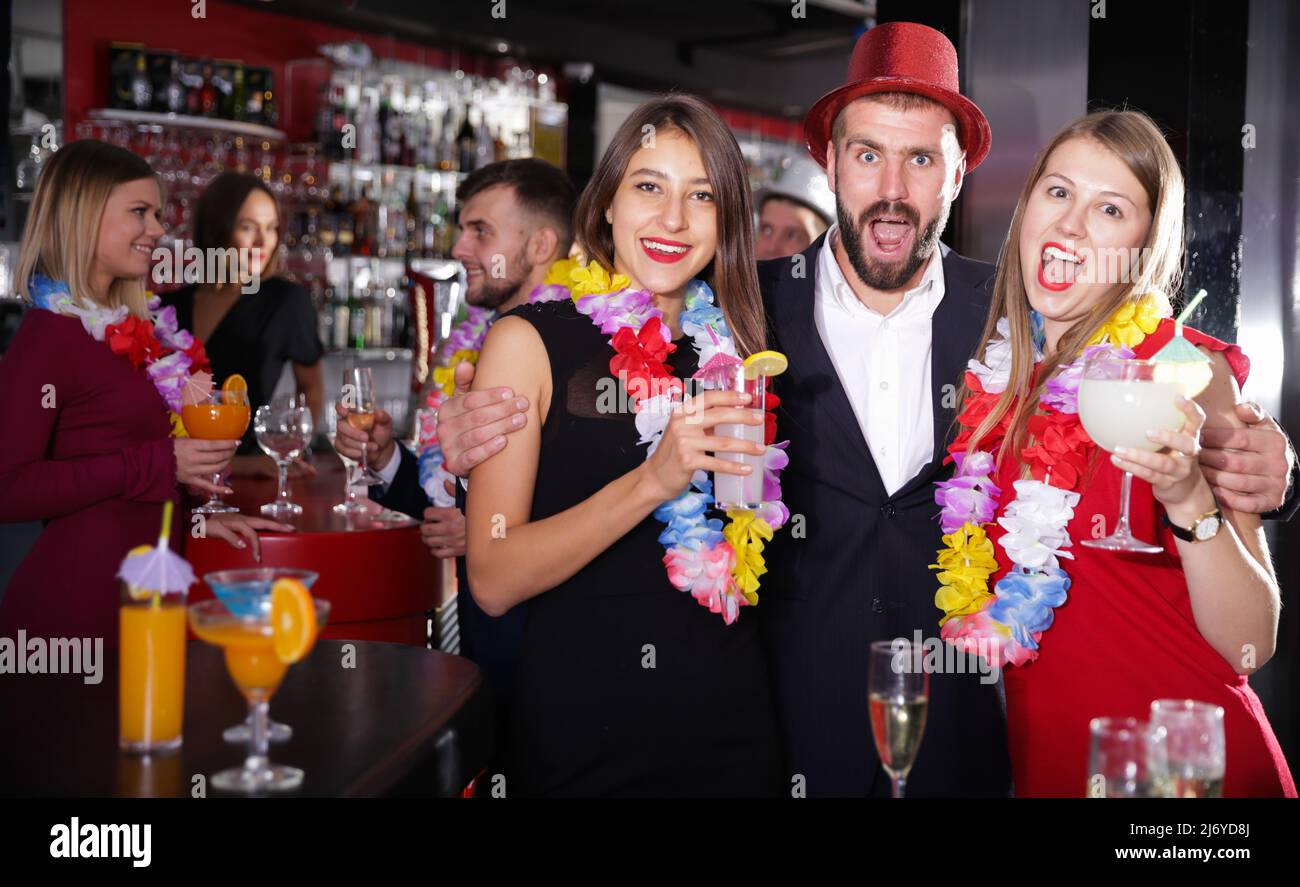 Man with female friends on Hawaiian party in bar Stock Photo - Alamy