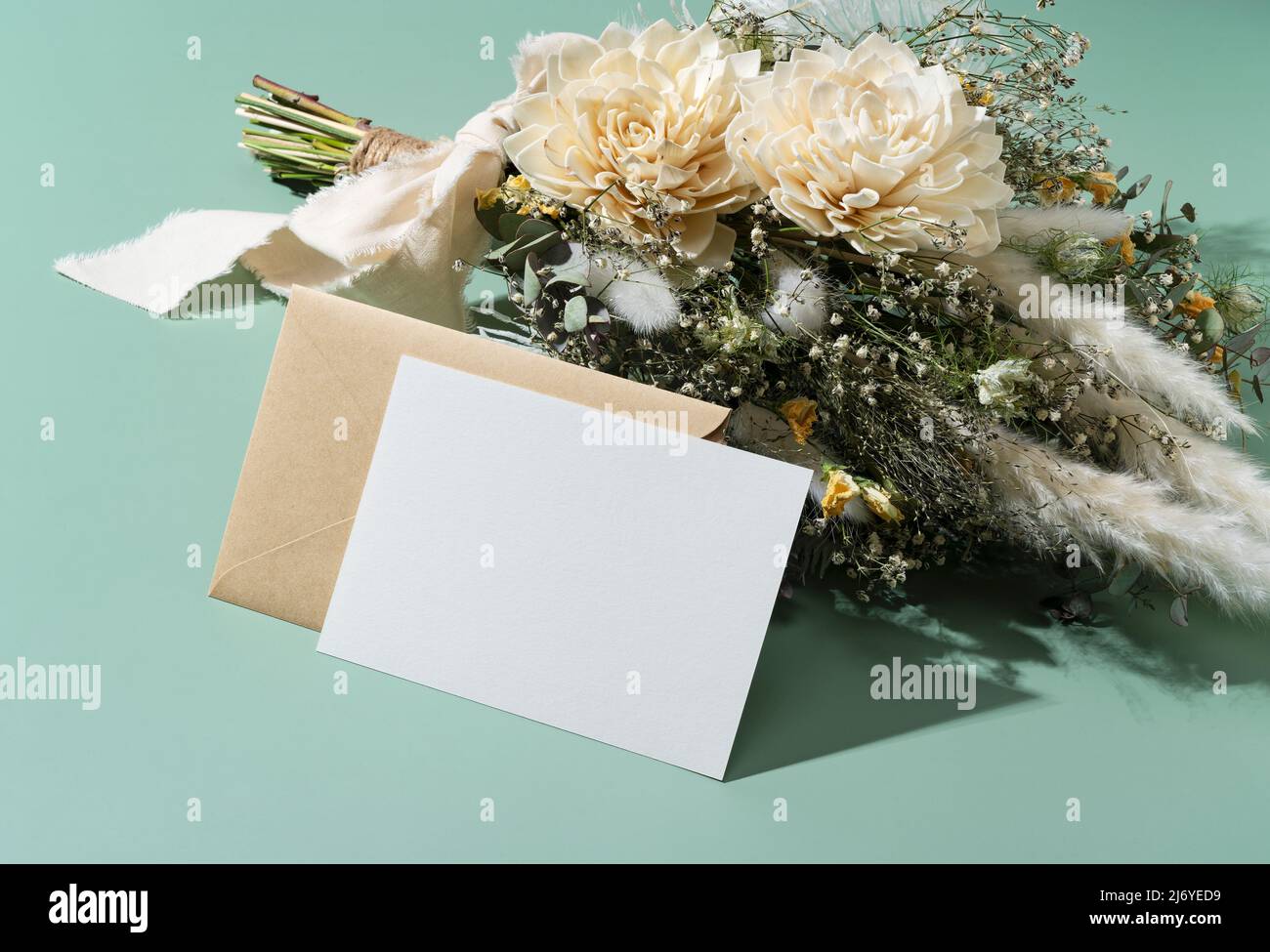 Dried flower bouquet and blank message card placed on green background ...