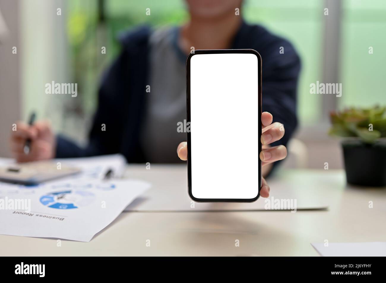 Close-up image, Female showing cellphone screen over her offie desk ...