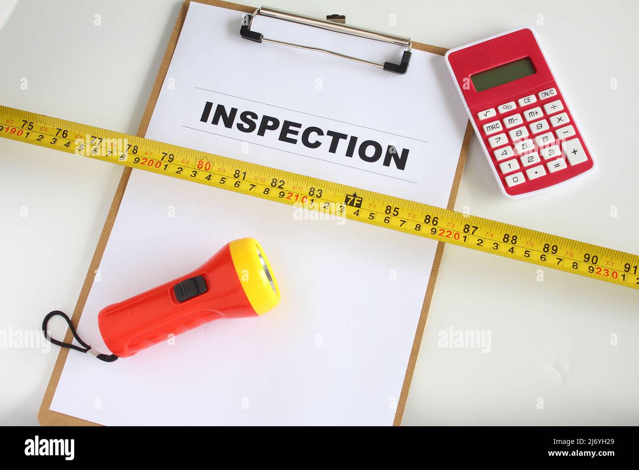 Inspection word on working paper with measuring tape and calculator ...