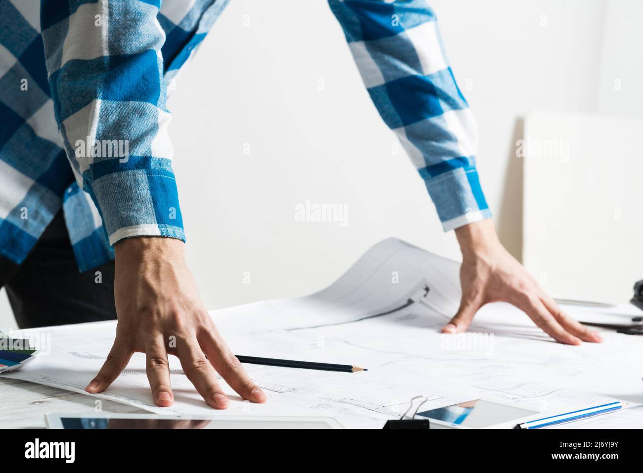 Architect standing near desk with paper blueprints Stock Photo - Alamy