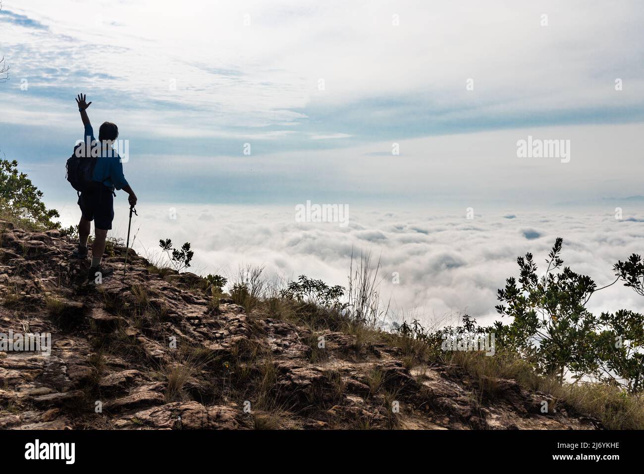 Hiker Asian man in silhouette standing on peak of mountain with cloud ...