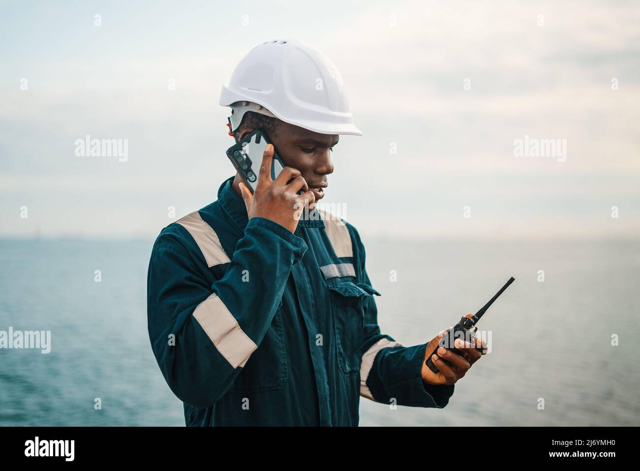 Black seaman with walkie talkie speaking on smartphone Stock Photo - Alamy