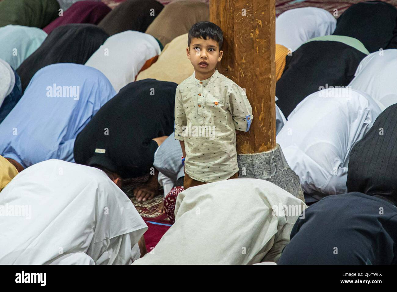 Kashmiri Muslim boy standing with wooden pillar as Muslim worshippers ...